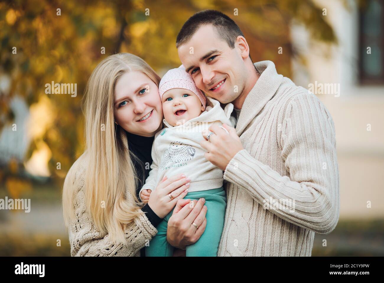 Young happy family smiling at camera and standing together Stock Photo ...