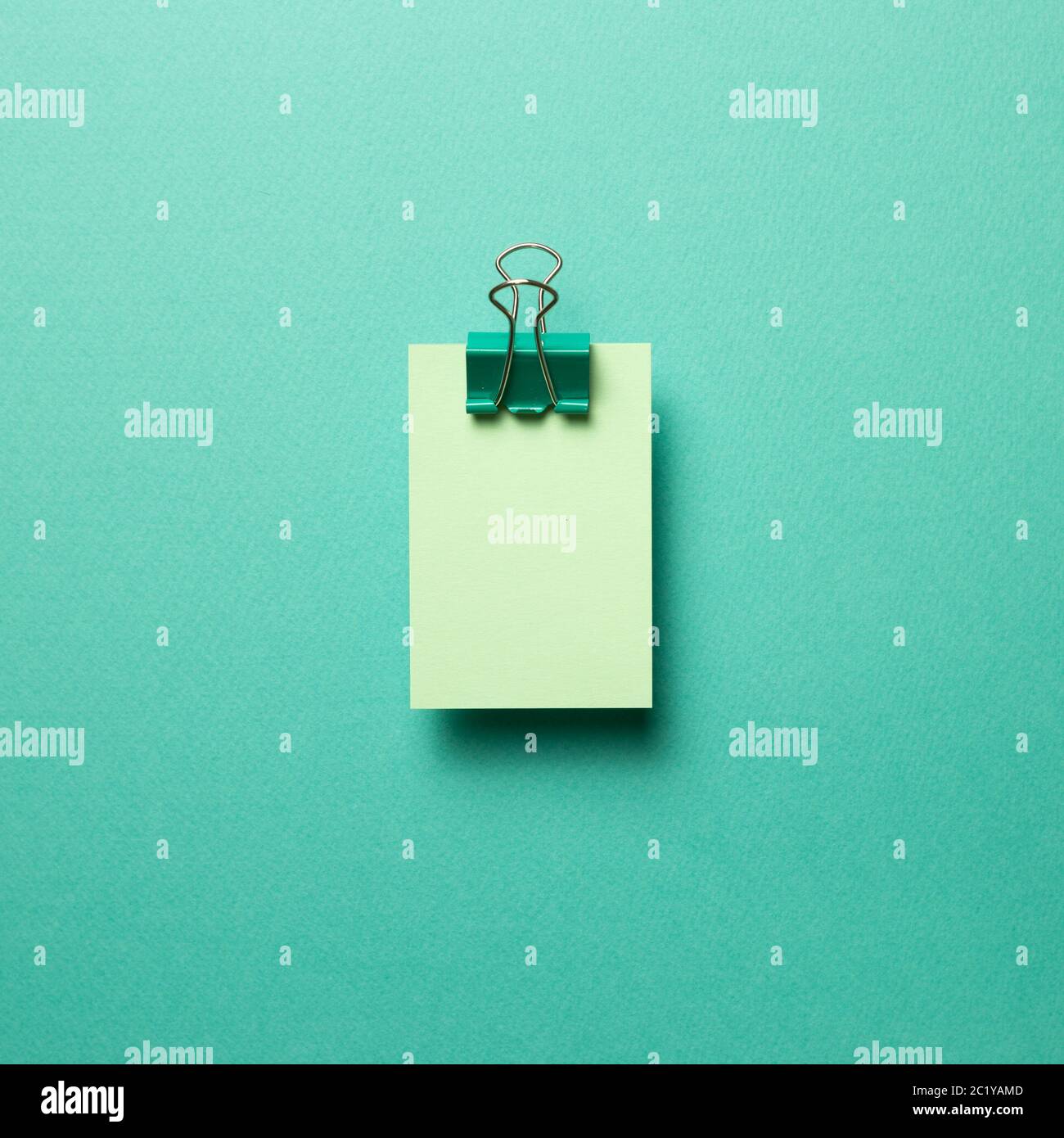 Green memo paper, sticky notes with green binder clip on mint green ...
