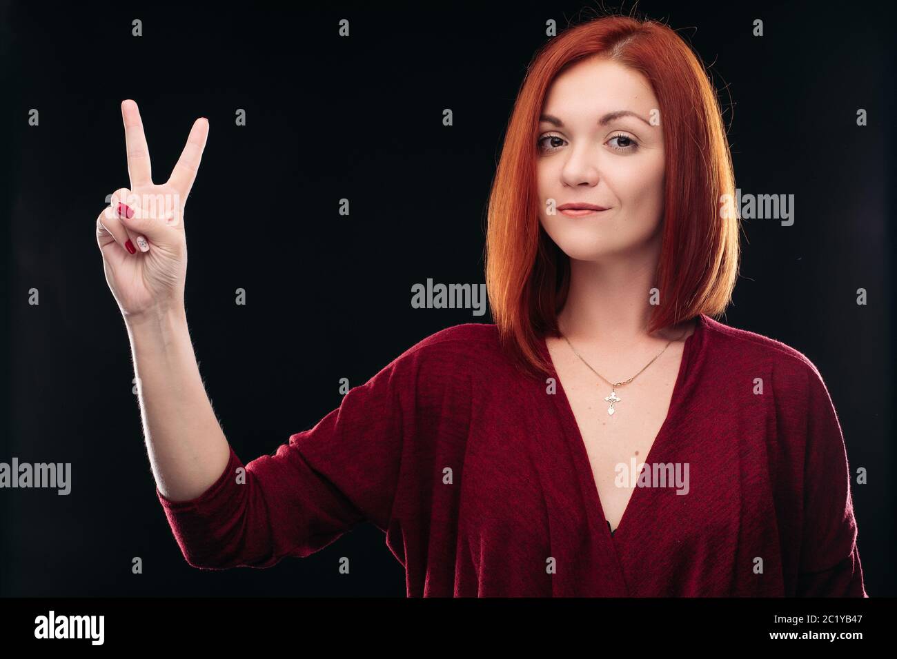 Attractive red haired girl holding hand with 2 finger up Stock Photo ...