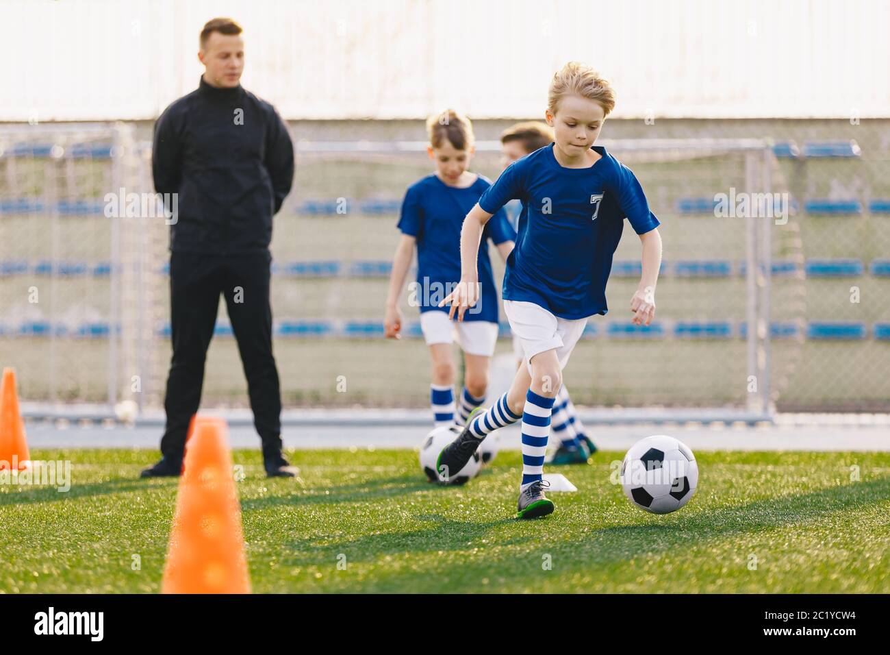 Sports physical education lesson. Children training soccer football on ...
