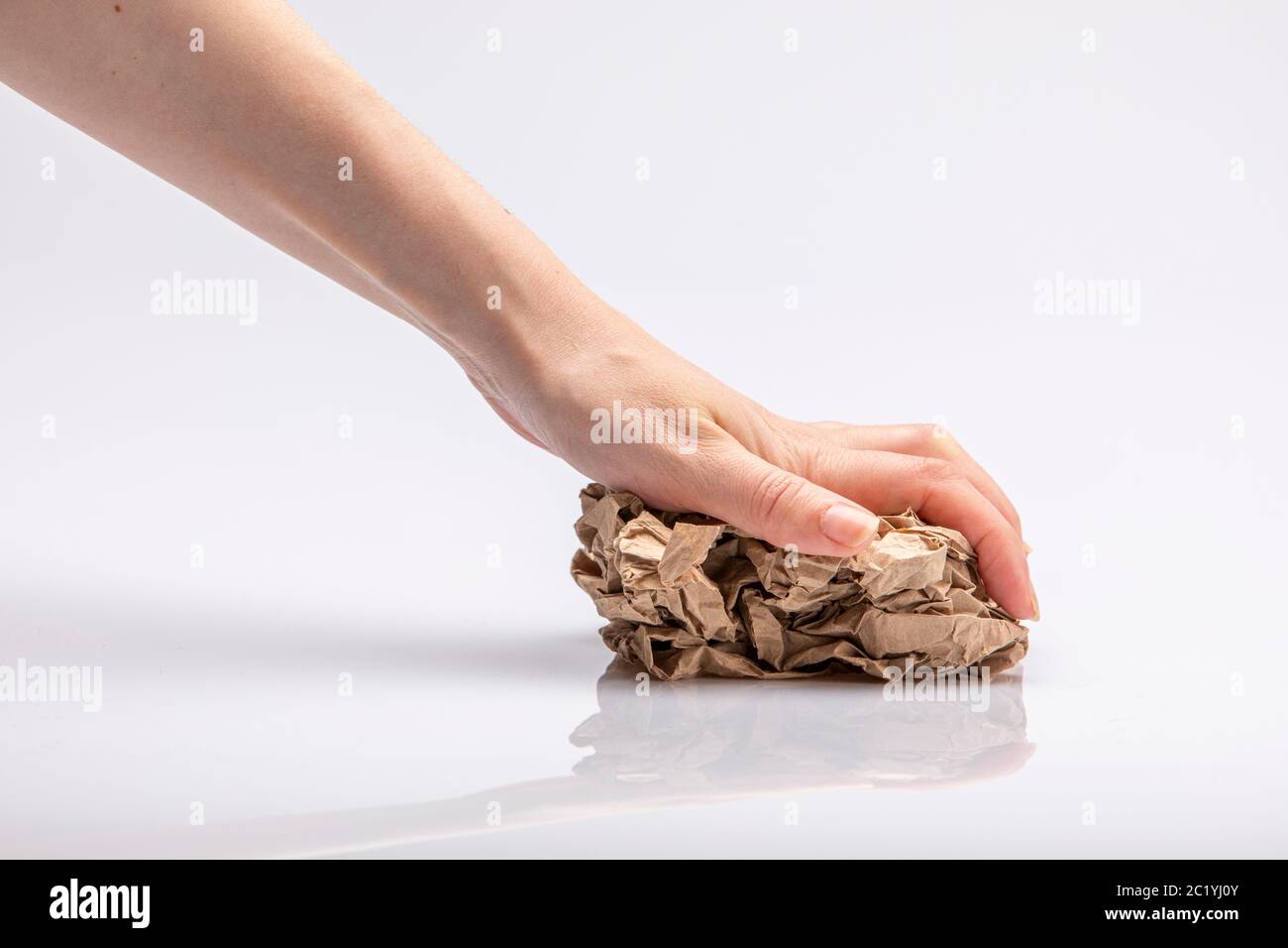 Close-up of a white people's hand crushing a crumpled piece of brown ...