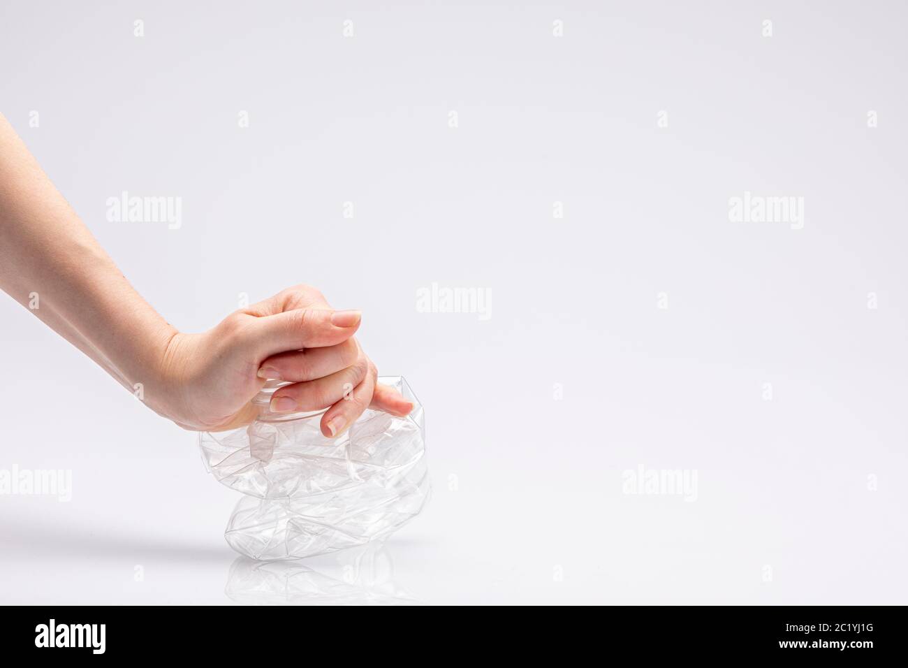 Close-up of a white people's hand crushing a crumpled plastic bottle in ...