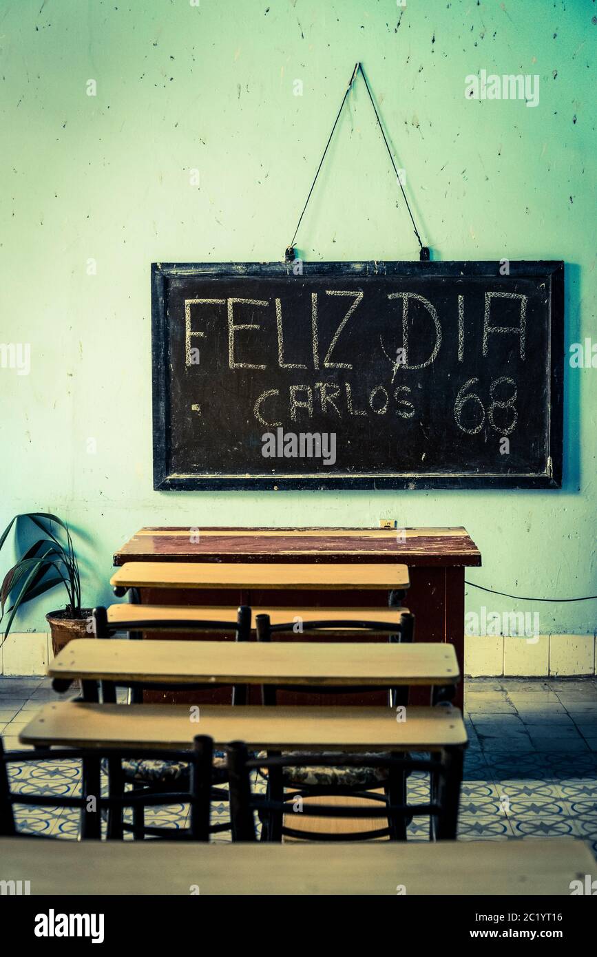 Old-fashioned classroom with blackboard on which is written in Spanish ...