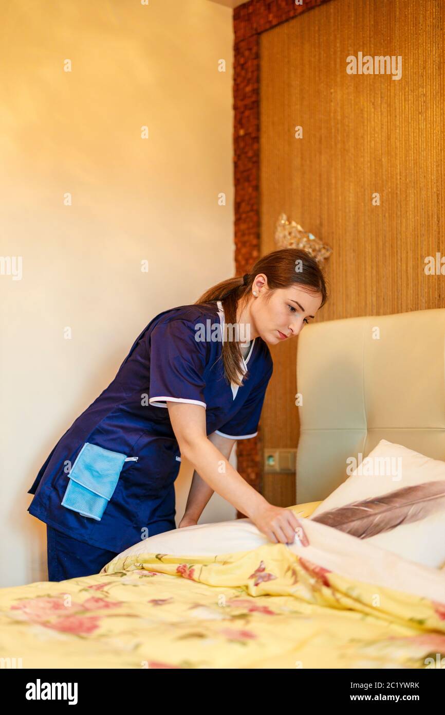 Maid in uniform making bed in hotel room Stock Photo - Alamy