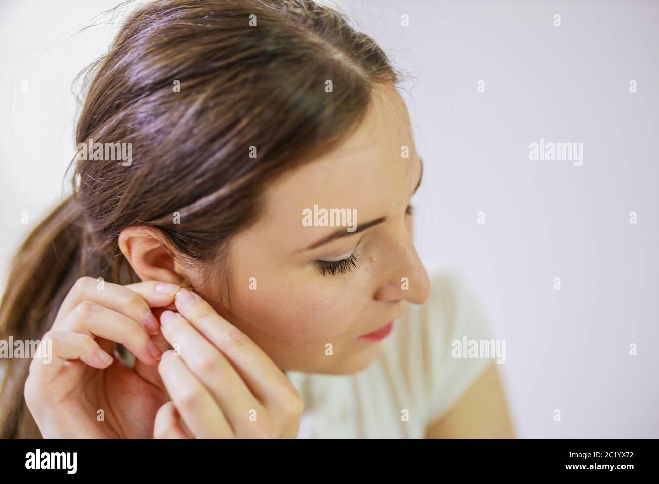 Woman putting on earrings hi-res stock photography and images - Alamy