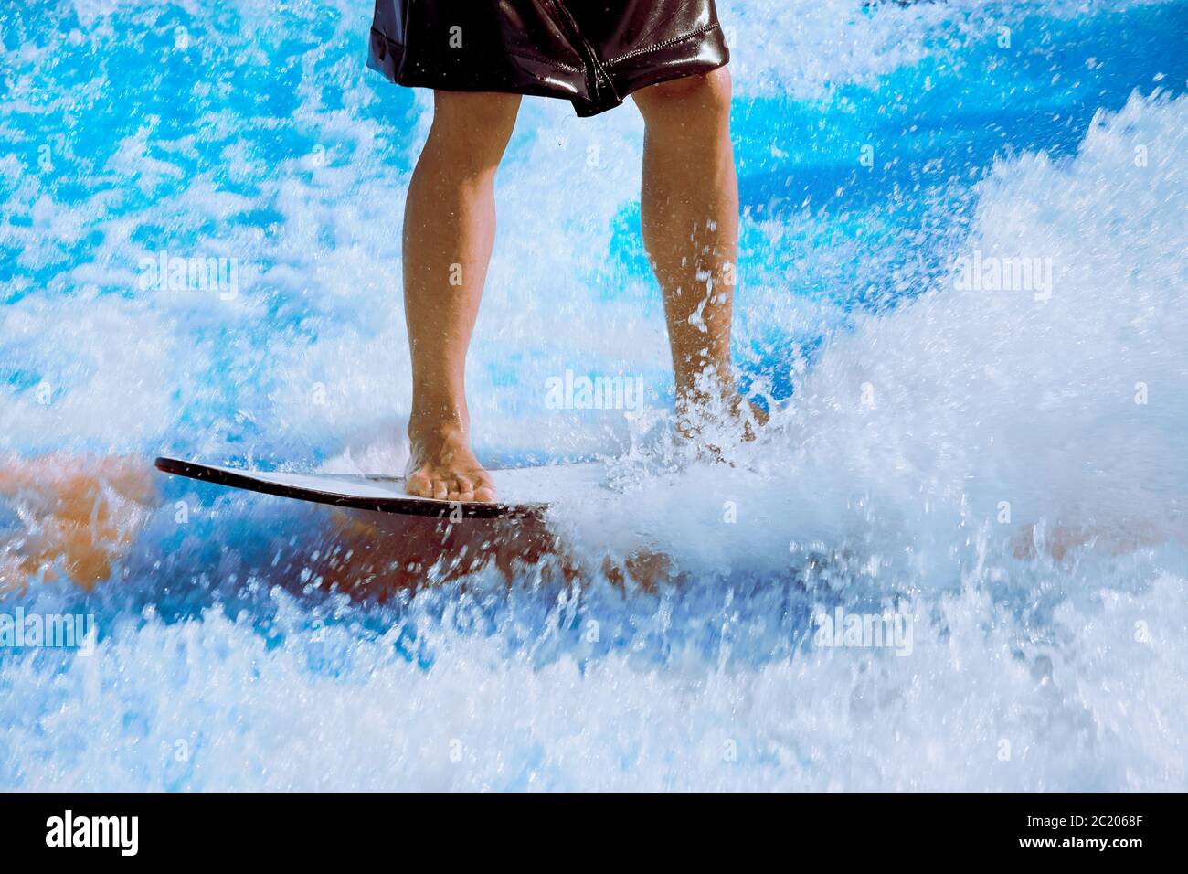 Man take wake surf, riding a surfboard or foot board along an outdoor ...