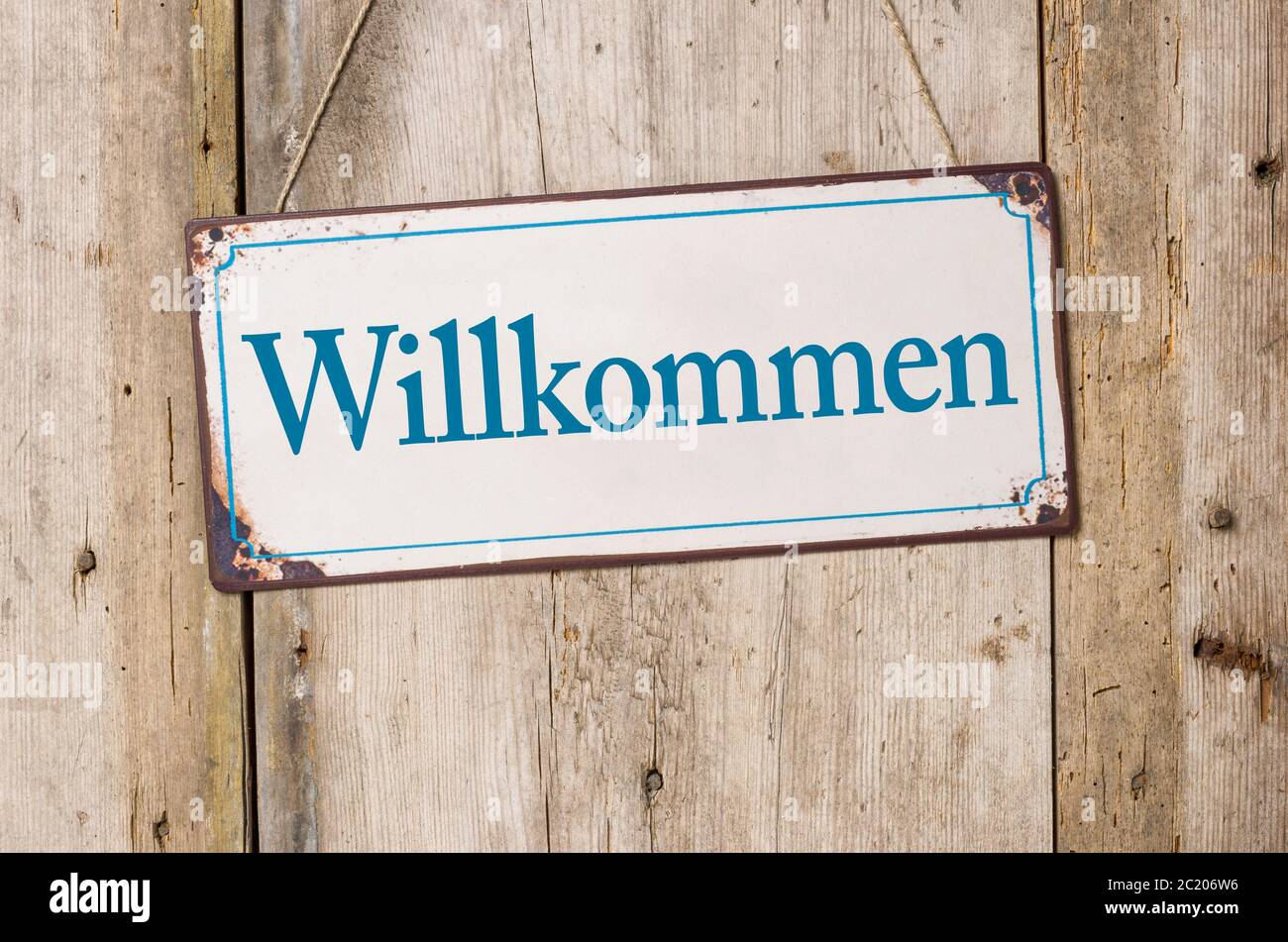 Old metal sign in front of a rustic wooden wall - Welcome - Willkommen ...