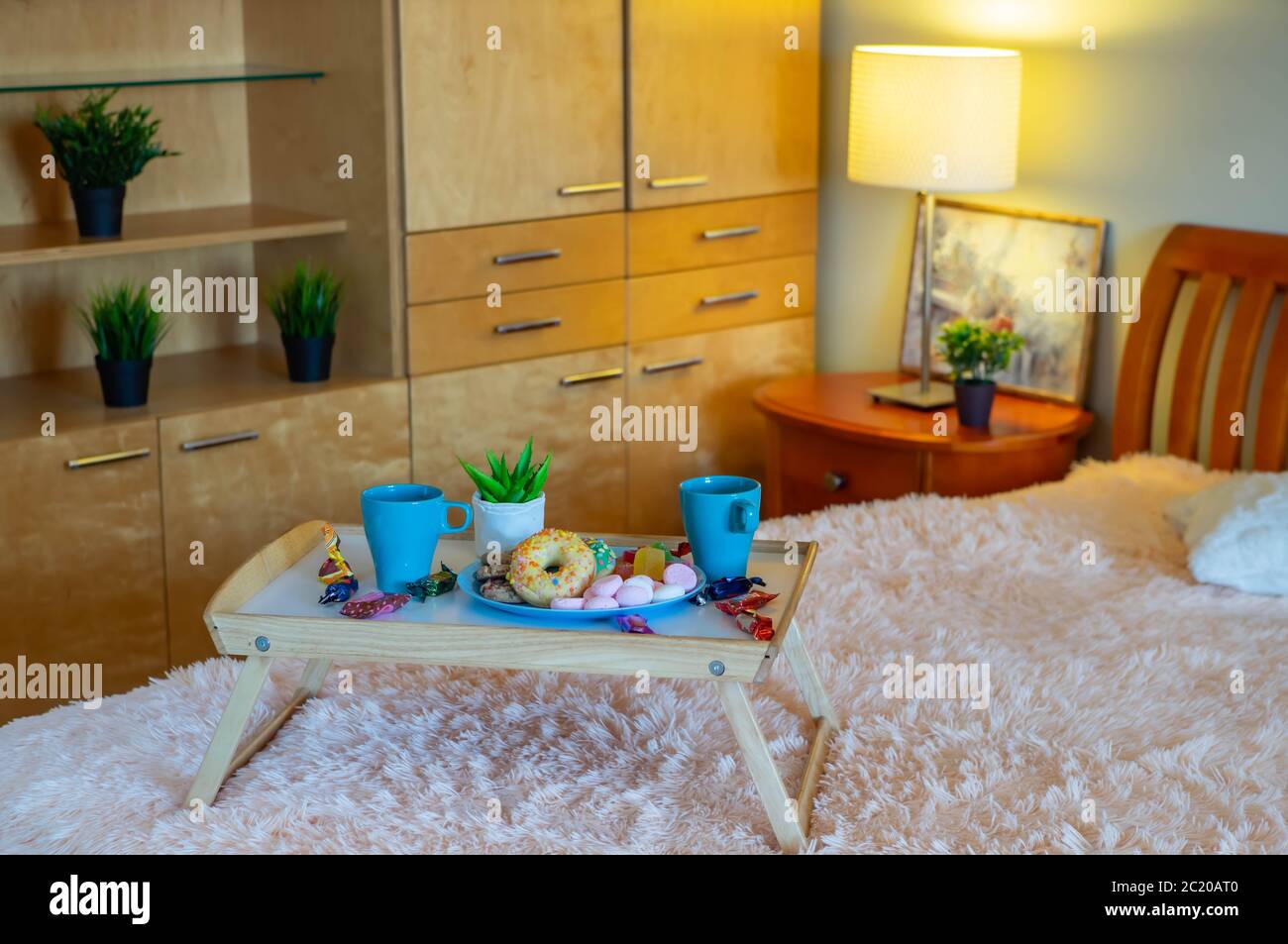 Tray with breakfast on the bed. Romantic composition. Couple of mugs ...