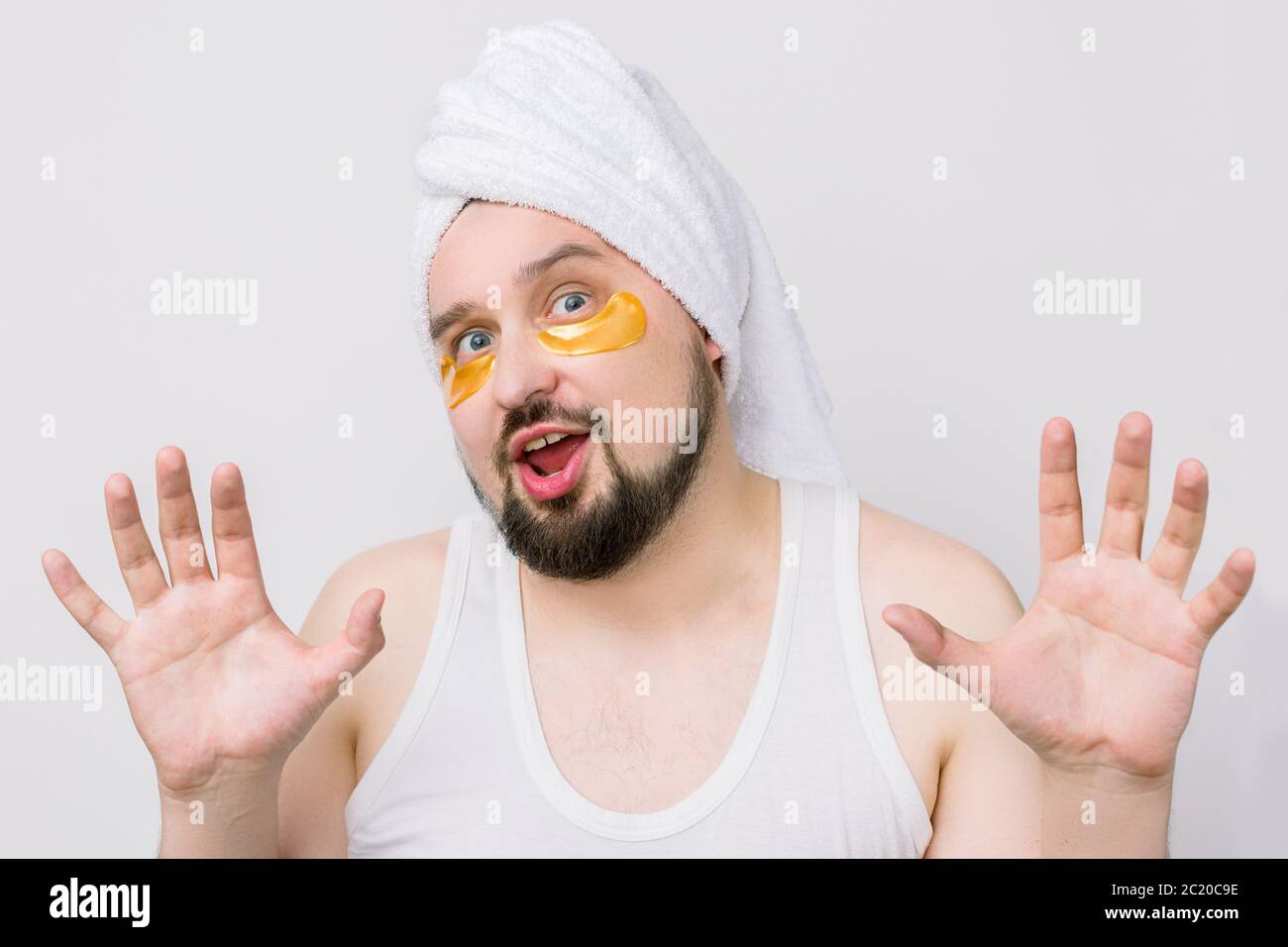 Photo of joyful excited shocked handsome bearded man with white towel on head, golden eye ...
