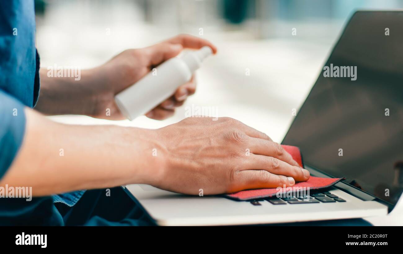 close up. man spraying spray on the surface of a laptop Stock Photo - Alamy