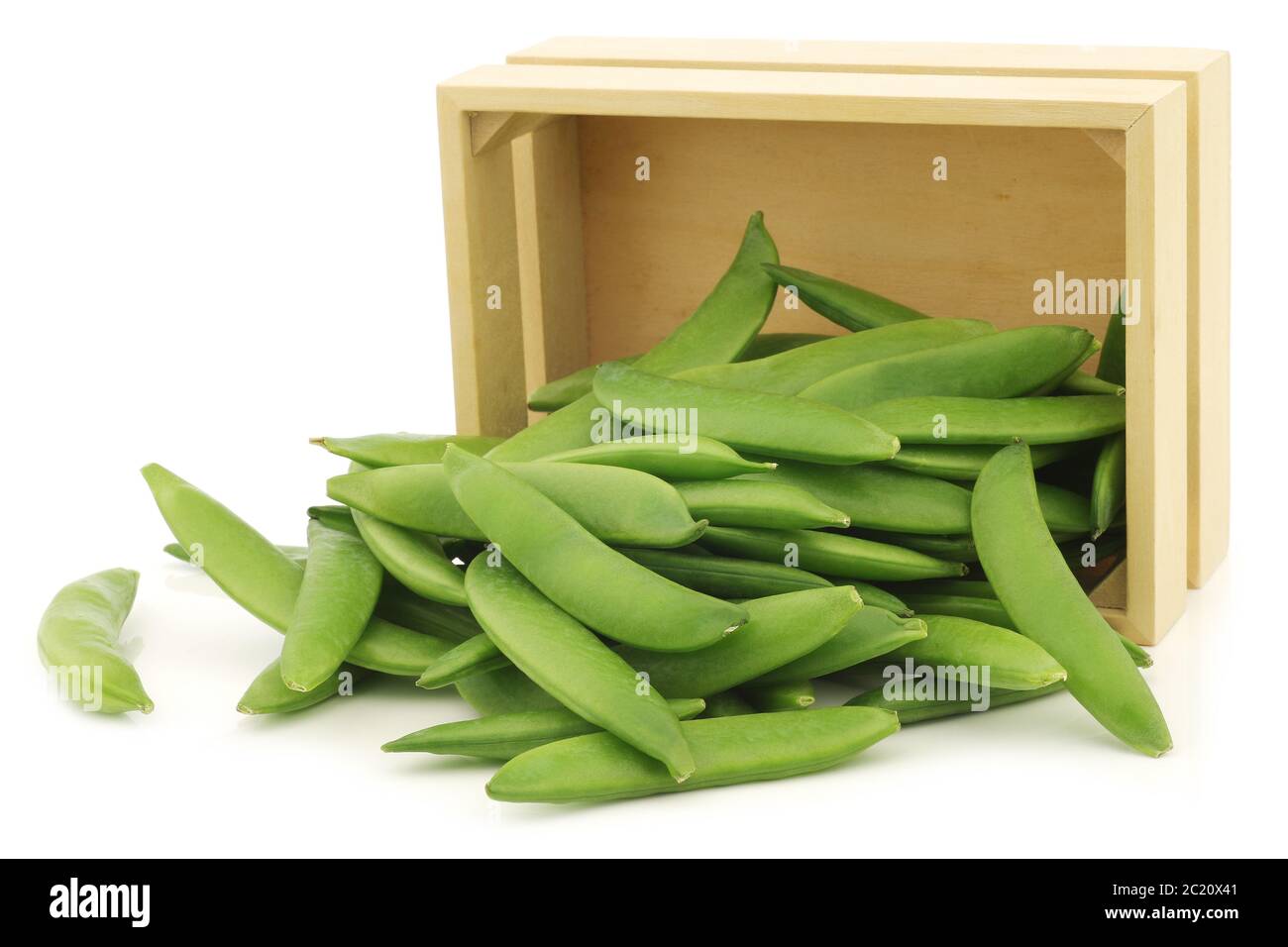 freshly harvested sugar snaps in a wooden box on a white background ...