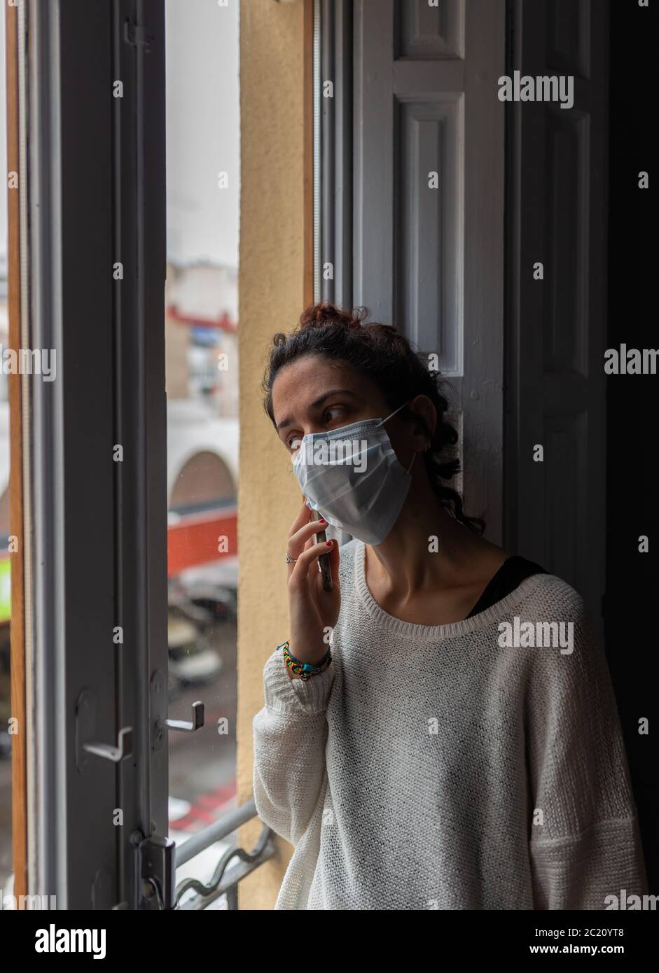 Woman portrait speaking on the phone while looking through the window ...