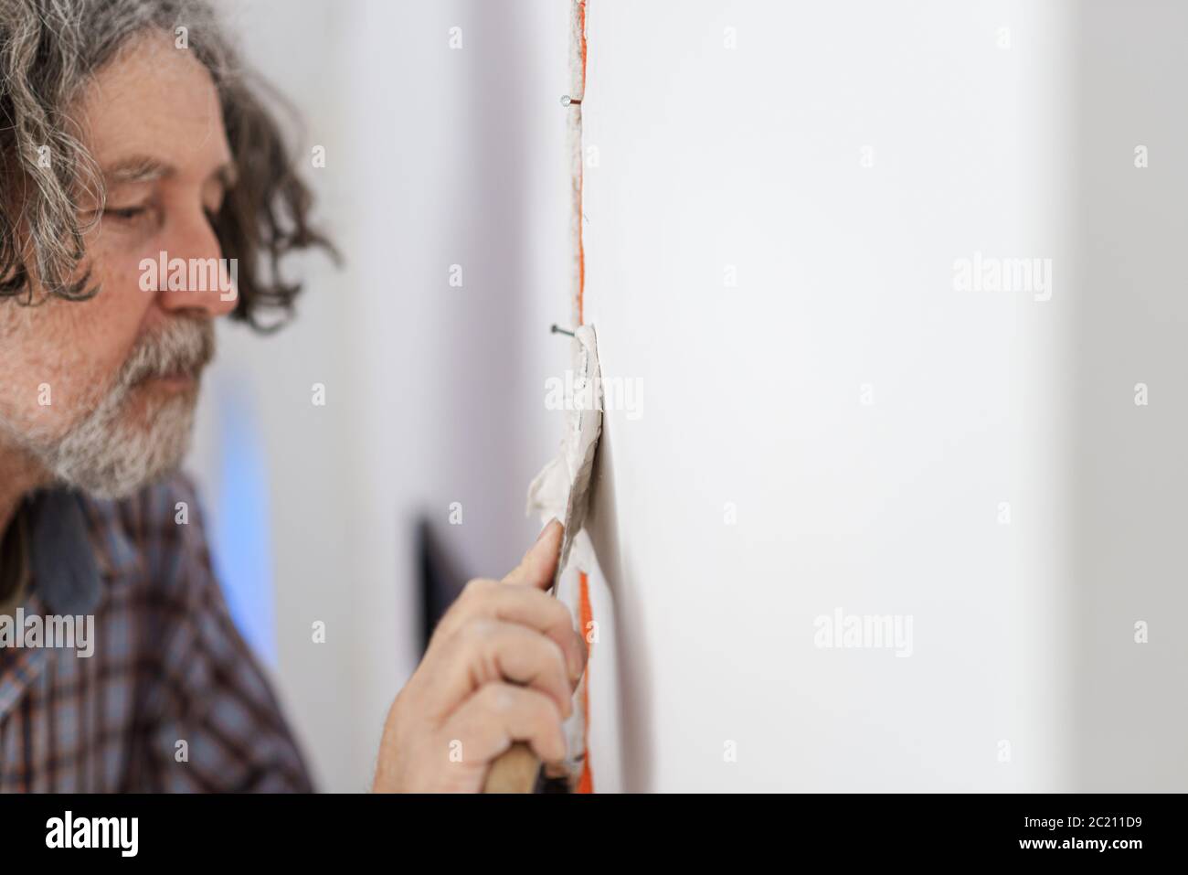 Senior man in a home diy project plastering an orange electrical tube ...