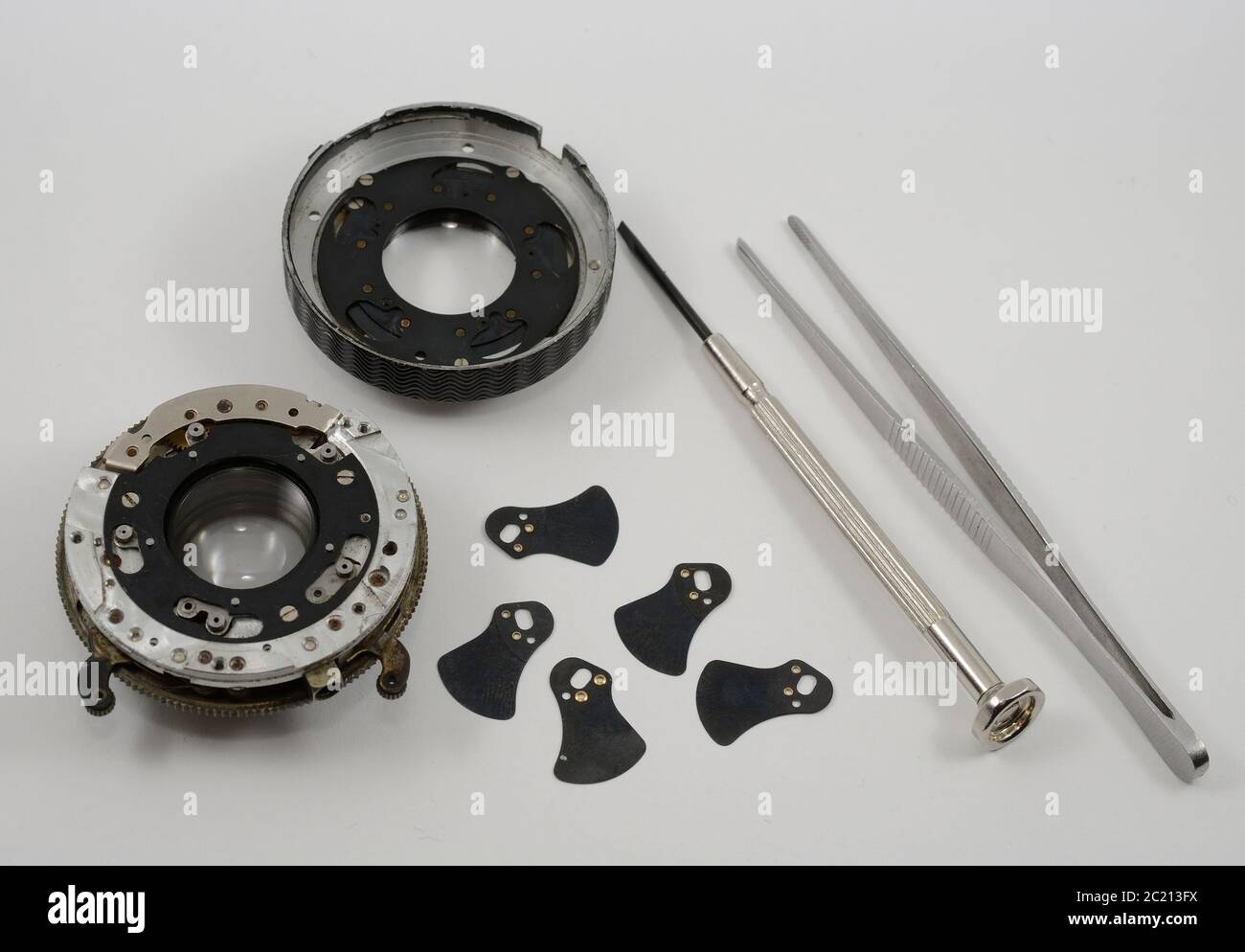old vintage disassembled lens, aperture blades, screwdriver and ...