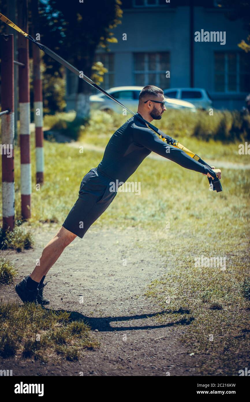 Fitness suspension straps man training with suspended lunge exercise in ...