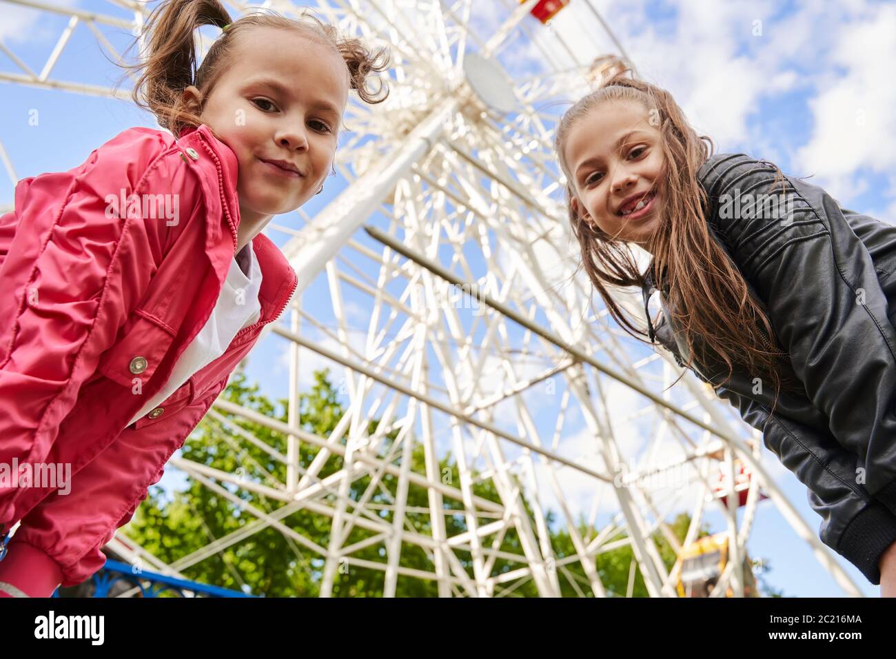 Two Girls Are having fun in amusement park. A Ferris Wheel Are On The ...