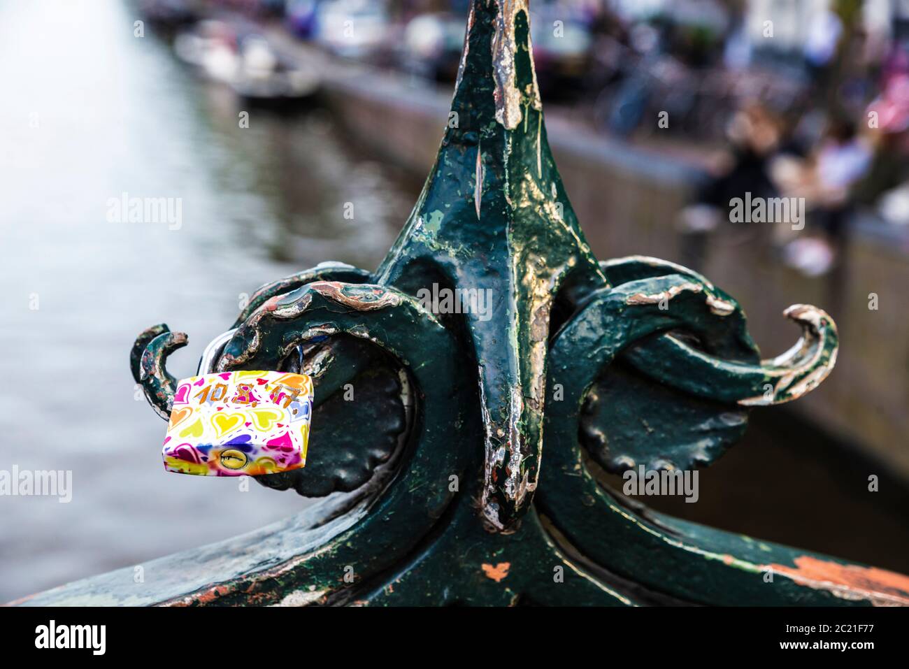 Padlock patterned with colored hearts tied on a railing of a bridge in ...