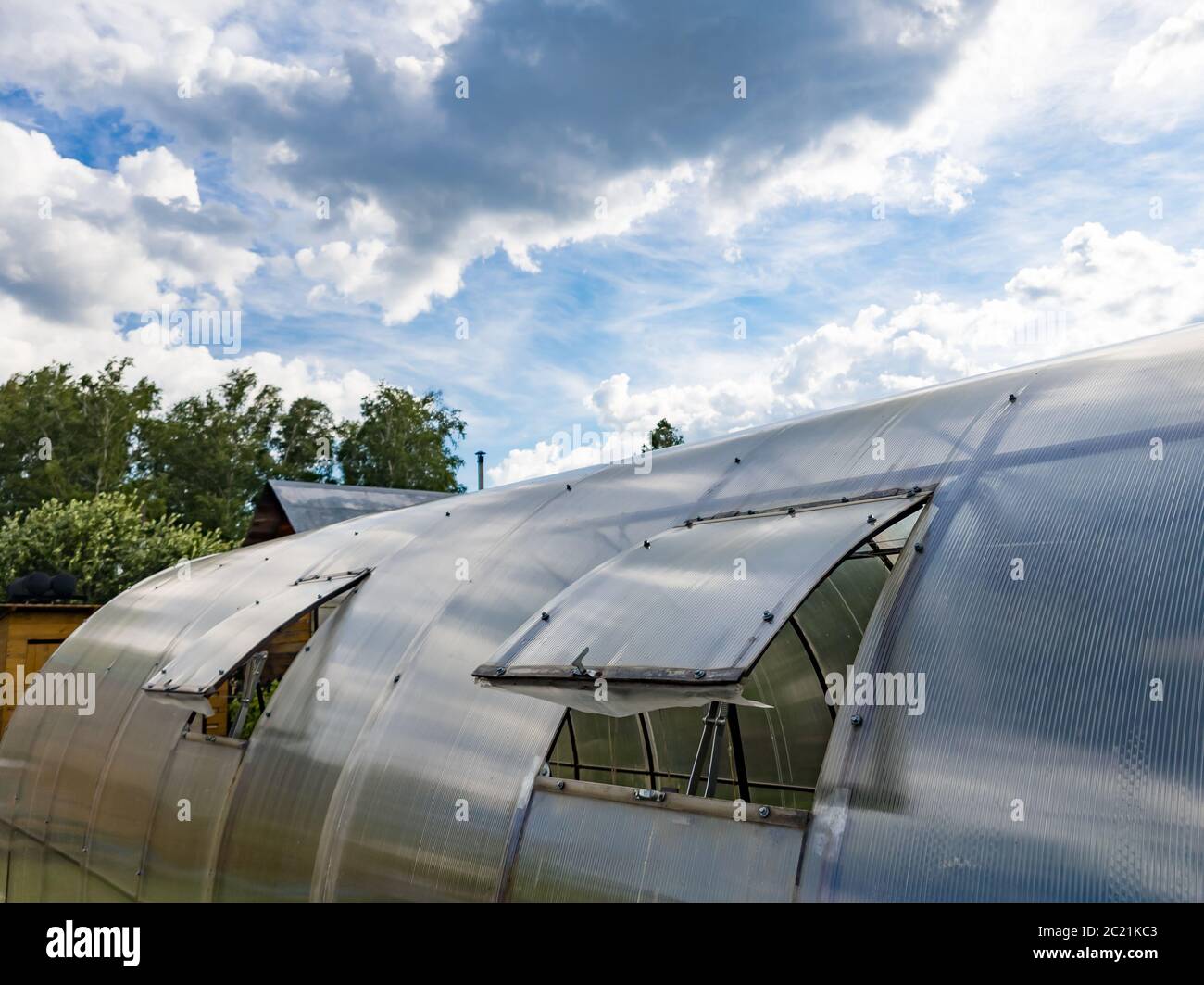 Automatic windows in the greenhouse outside against the sky and trees ...
