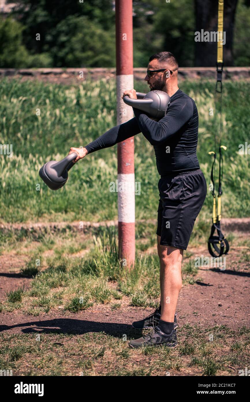Kettlebell weightlifting fit man lifting crossfit weight at outdoor gym ...