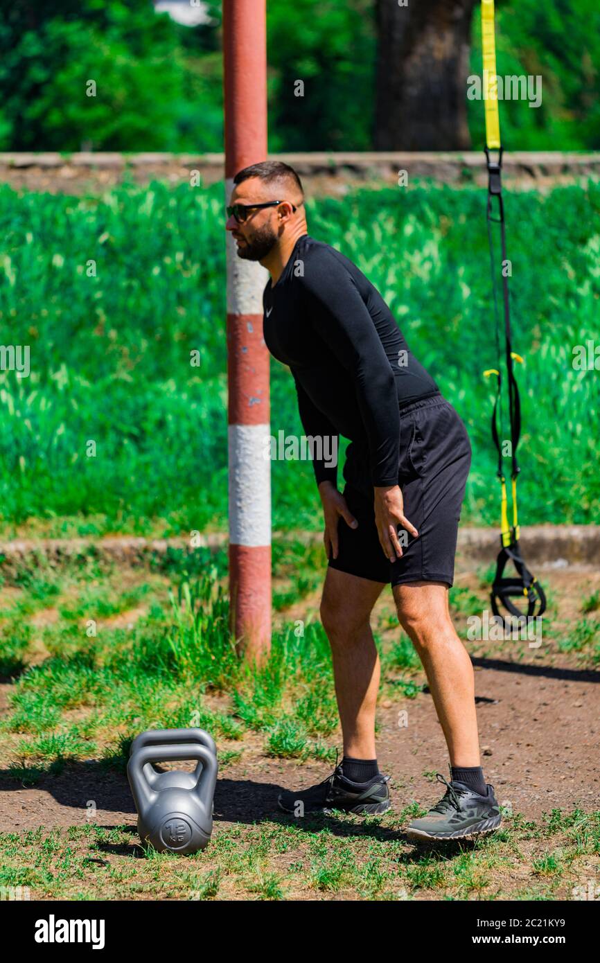 Kettlebell weightlifting fit man lifting crossfit weight at outdoor gym ...