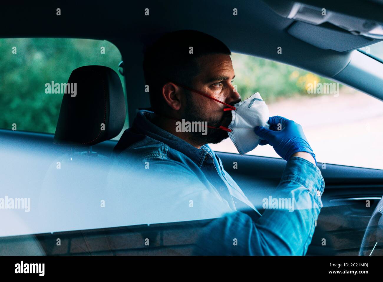 Driver adjusting his face mask in the car. Driving with COVID-19 ...