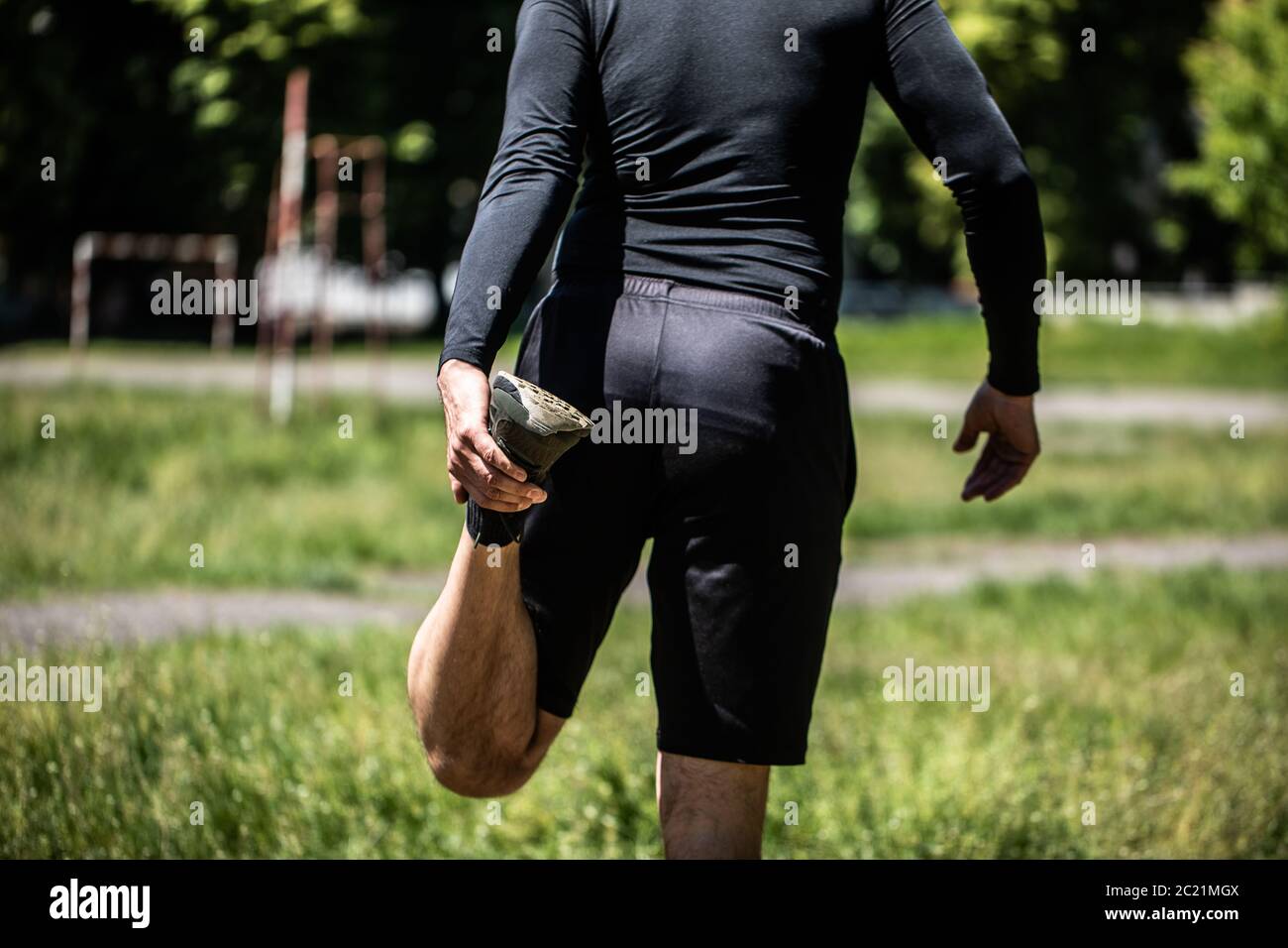 Outdoors image of muscular young man streching out against nature ...