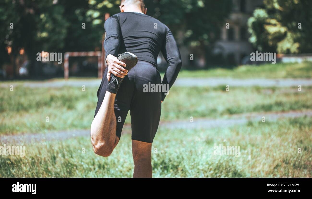 Healthy young man exercising and streching out on green lawn ...