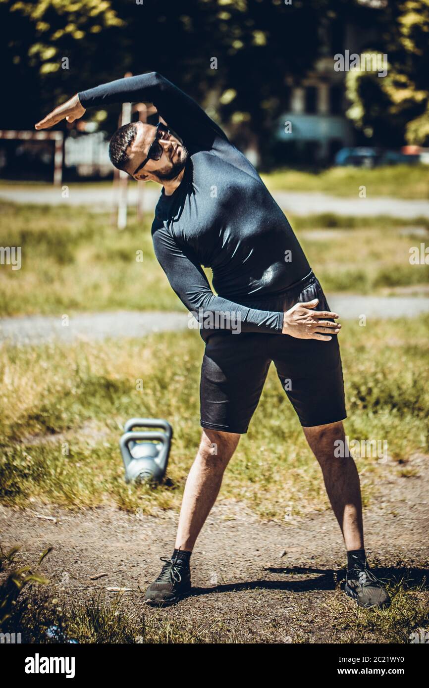 Young man doing physical exercise by streching his body with hands and ...