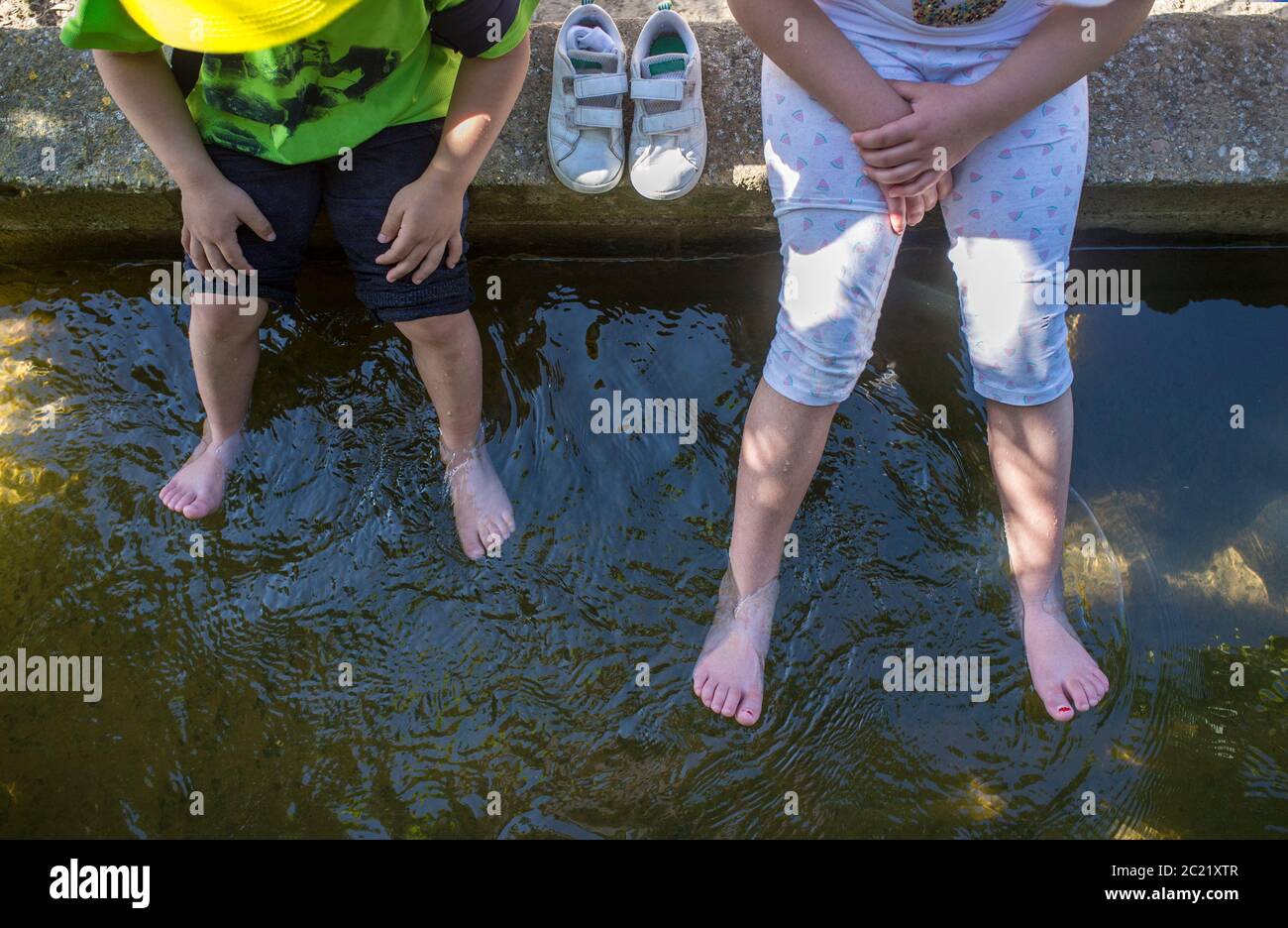 Children refreshing their feet into irrigation canal. Summer ...