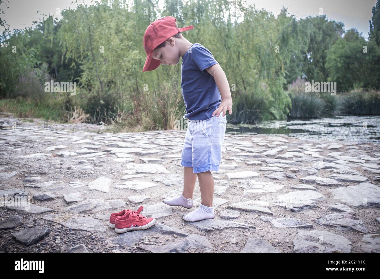 Little boy feel his feet wet after walking into the brook. Discovering ...