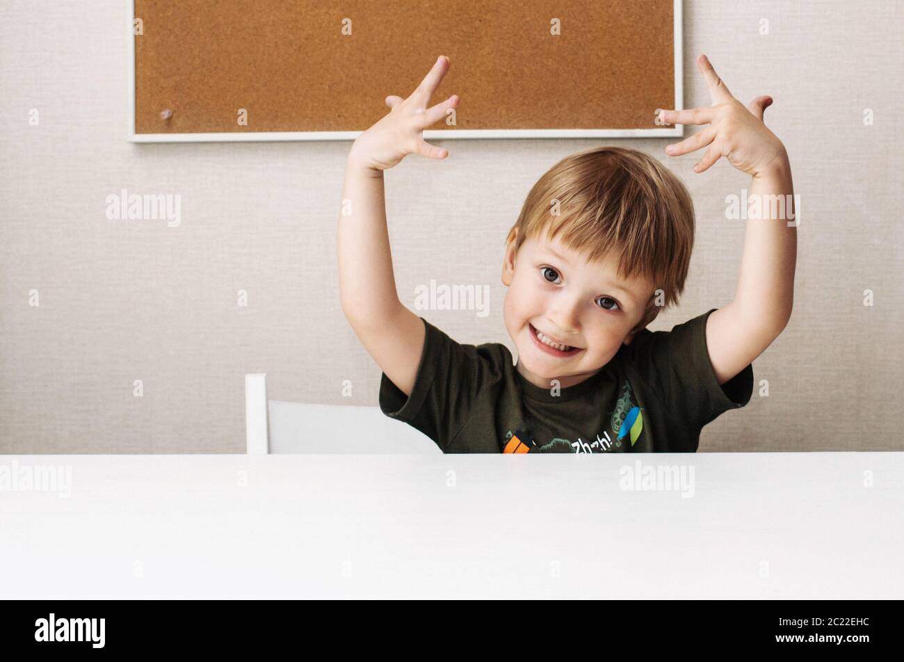 Funny little boy at the writing desk grimaces Stock Photo - Alamy