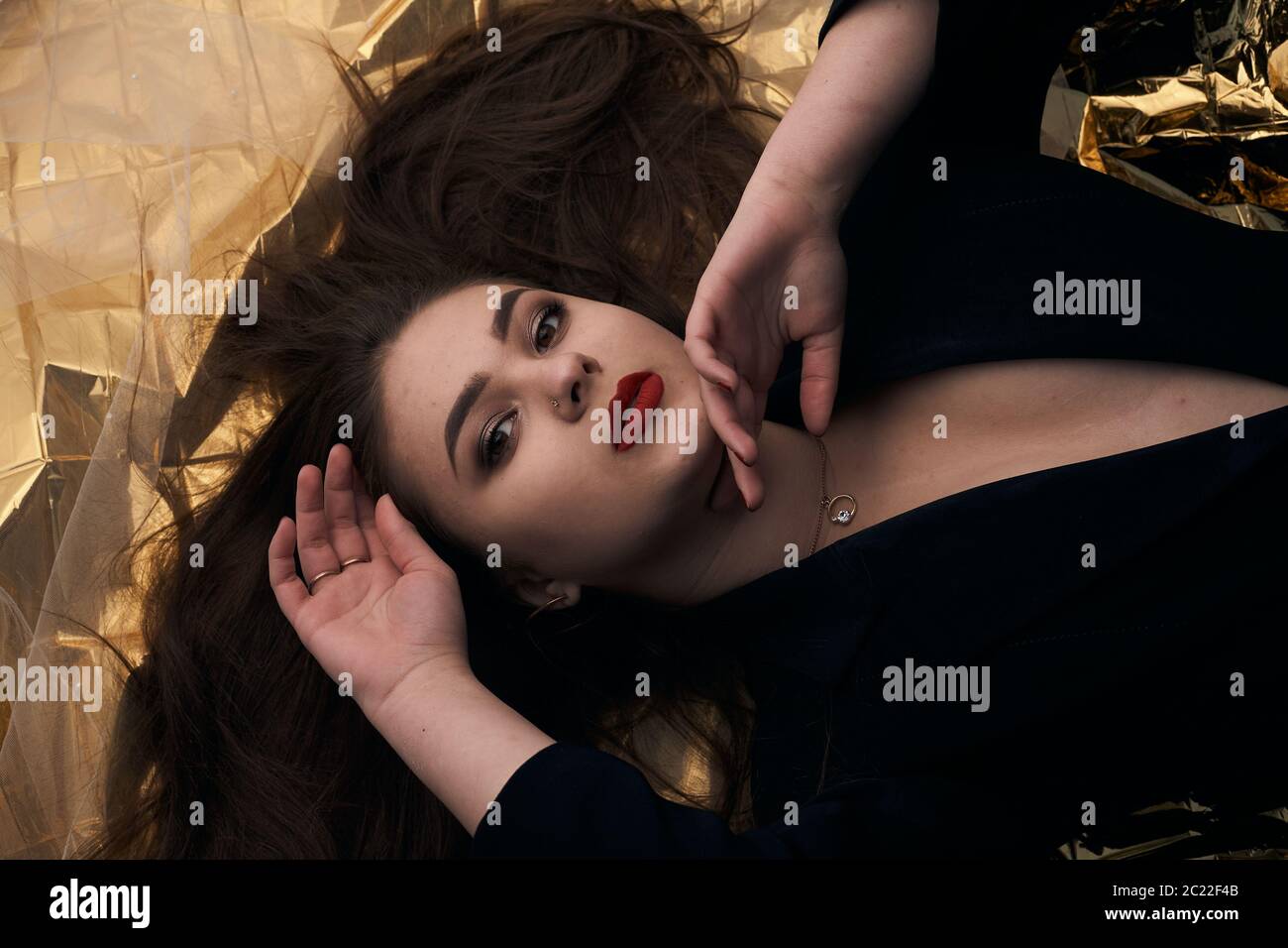 Beautiful makeup of a chubby girl lies on a gold foil Stock Photo - Alamy