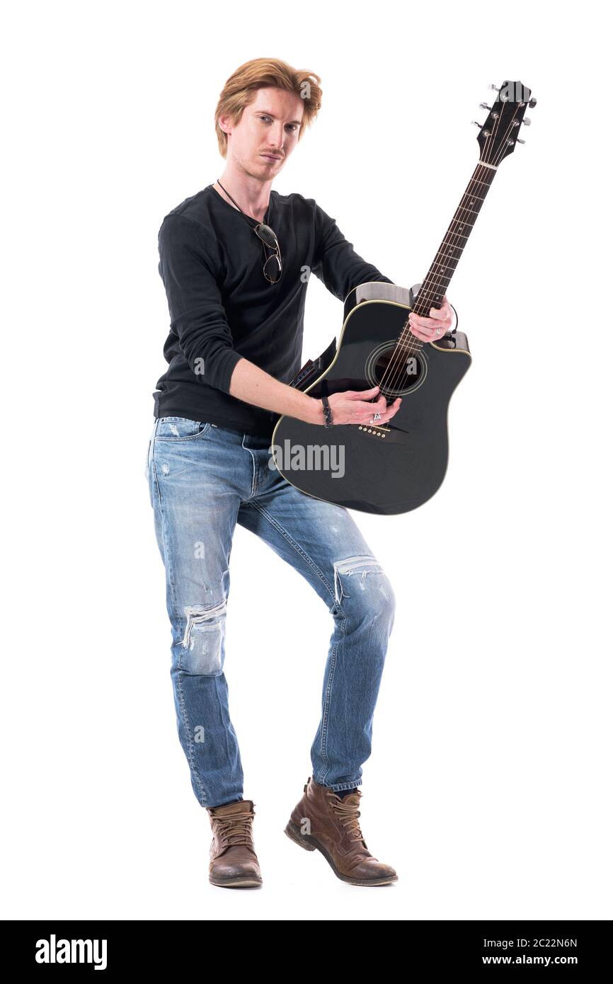 Self assured handsome guitarist playing acoustic guitar looking at ...