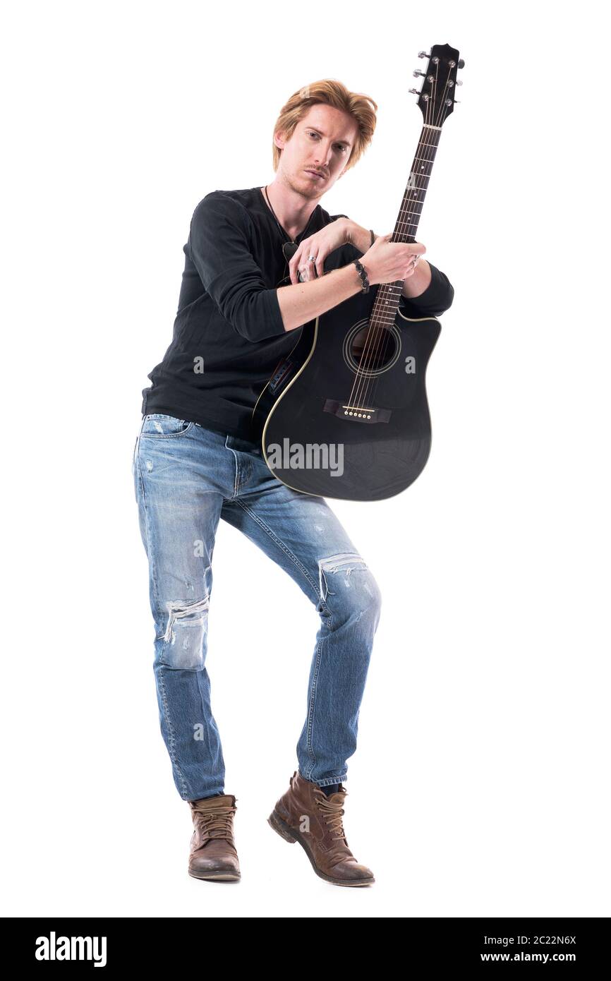 Confident cool young handsome rocker posing with his acoustic guitar ...