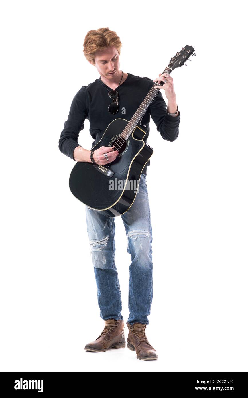 Young handsome guitarist man playing acoustic guitar looking down and ...