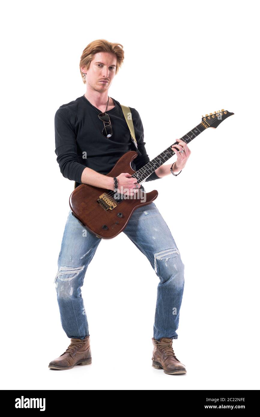 Confident hard rock music guitarist playing electric guitar looking at ...