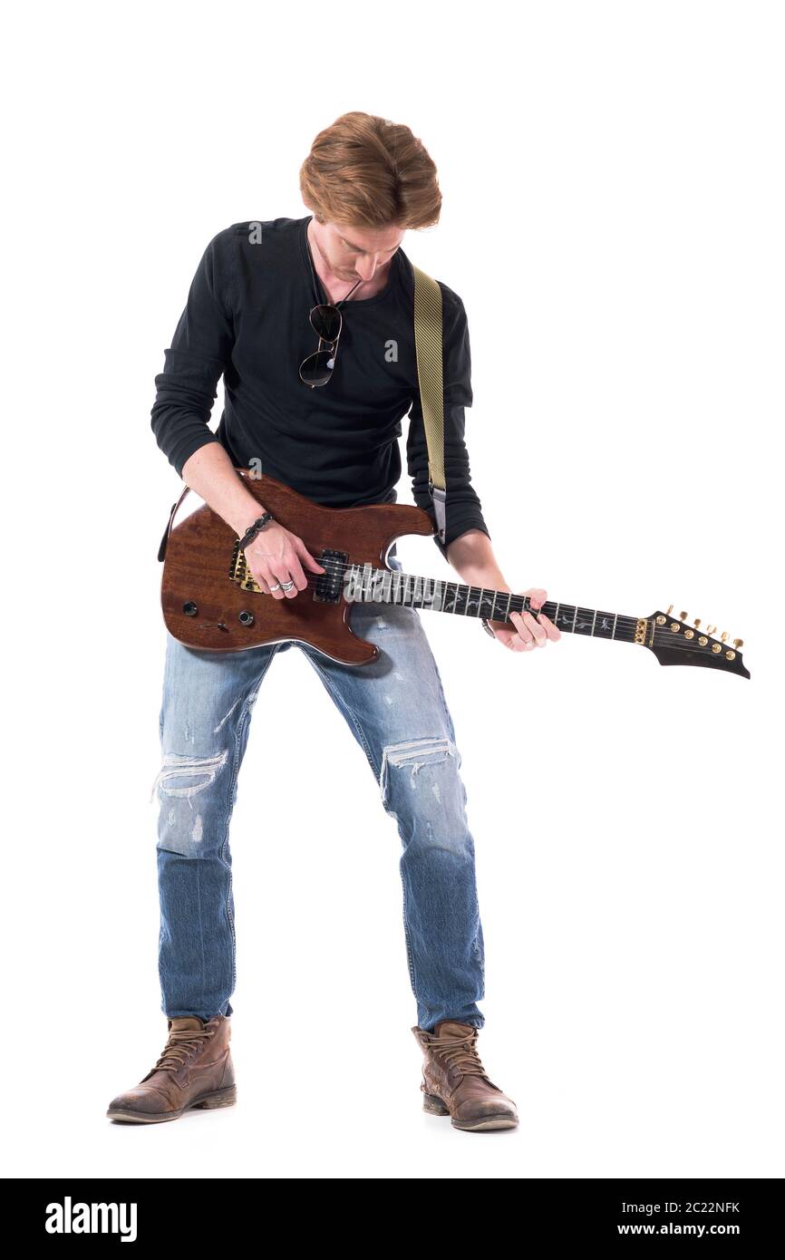 Young stylish rocker playing rock music on electric guitar looking down ...