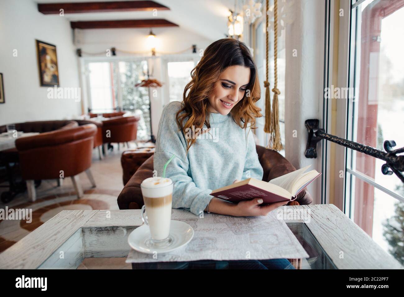 Happy girl reading interesting book in cafe Stock Photo - Alamy