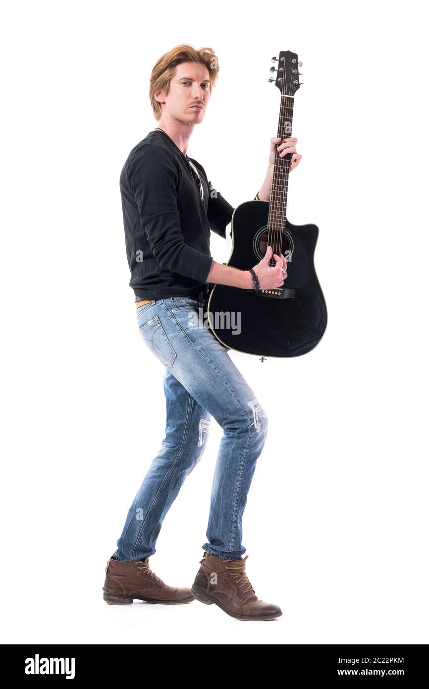Side view of confident young rocker musician playing acoustic guitar ...