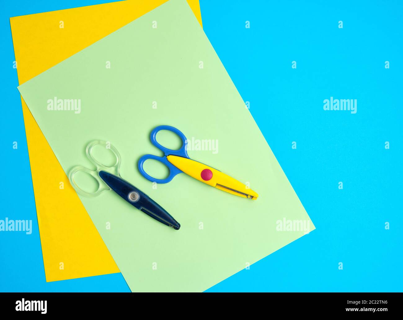 pair of plastic scissors and colored paper on a blue background, back ...