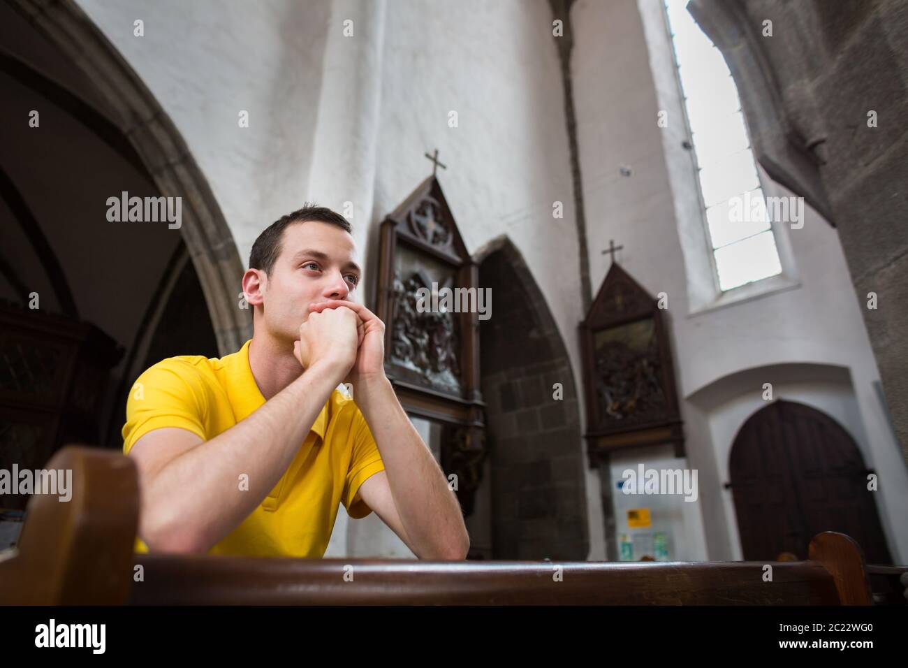 Handsome young man praying in a church Stock Photo - Alamy