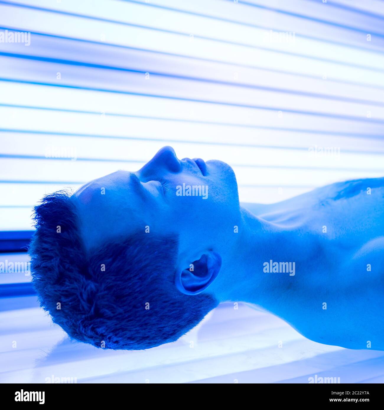 Handsome young man relaxing during a tanning session in a modern ...