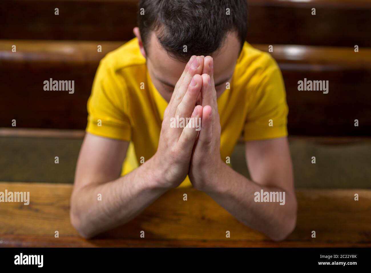 Young man praying in church hi-res stock photography and images - Alamy