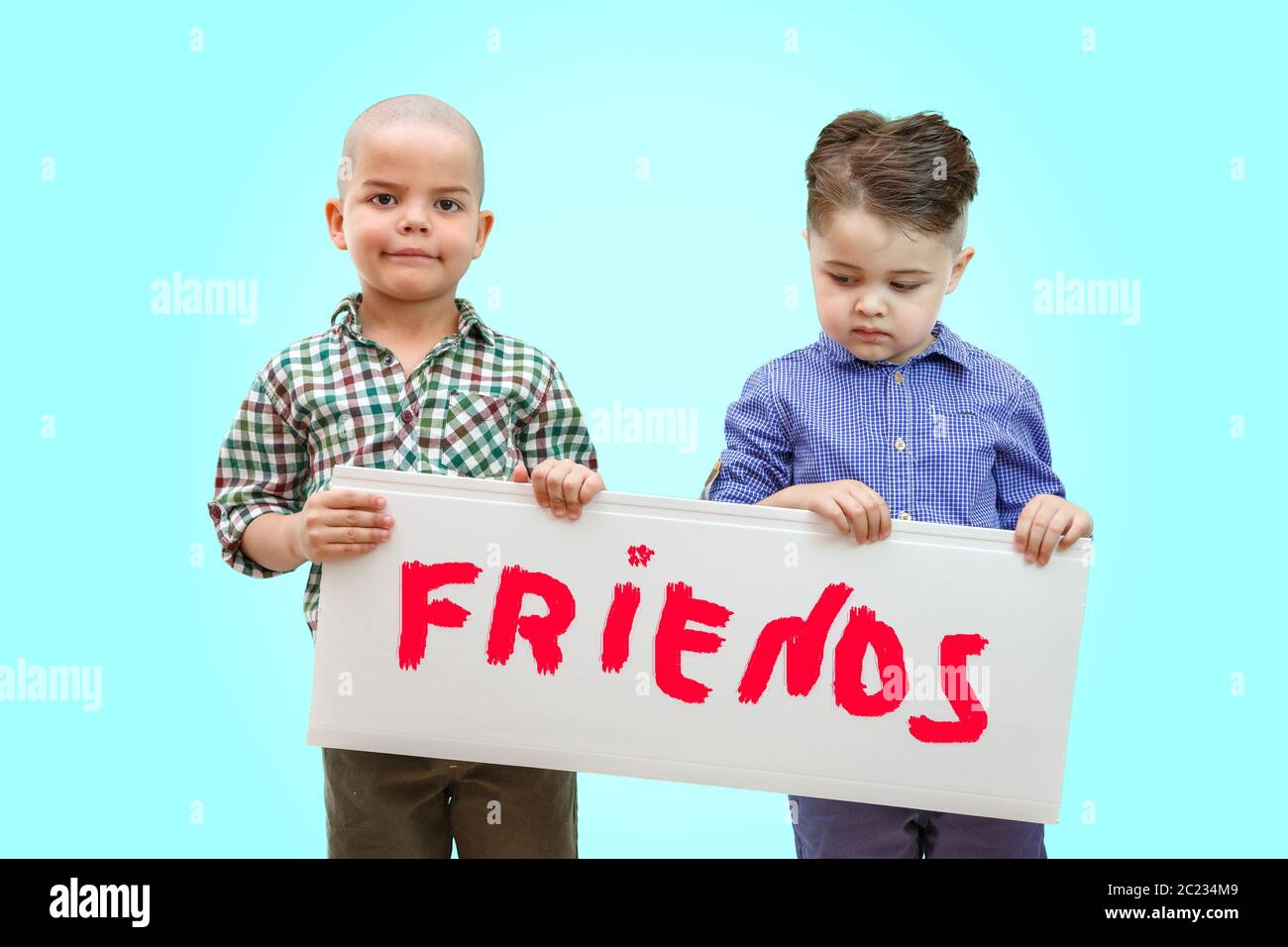 two boys holding a sign "Friends" in the hands. In light background ...
