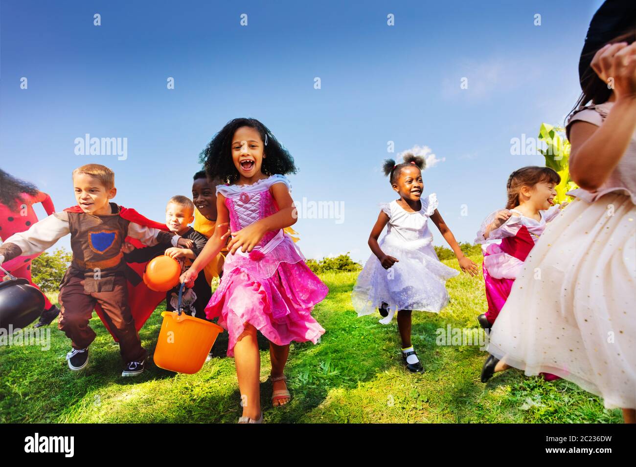 Large group of little kids run in Halloween costume on the lawn with ...
