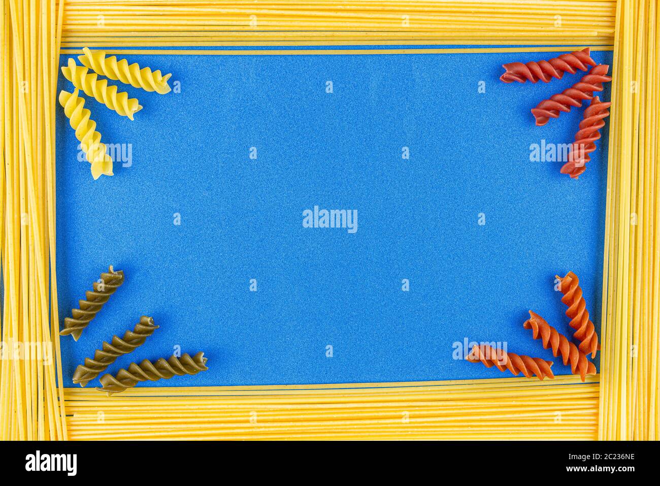 Frame made of spaghetti pasta on a blue foam background, colorful ...