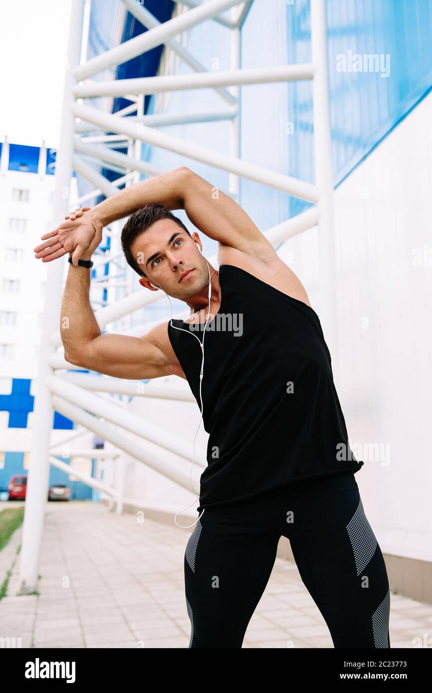 Muscular strong man doing stretching exercises for body during training ...