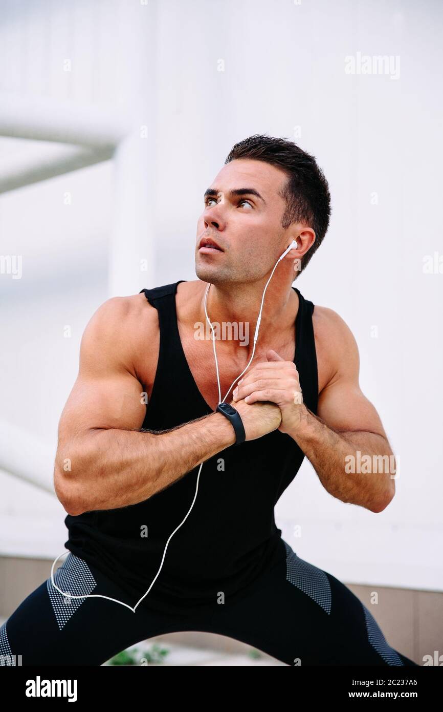 Young muscular guy preparing to workout, doing physical exercises ...