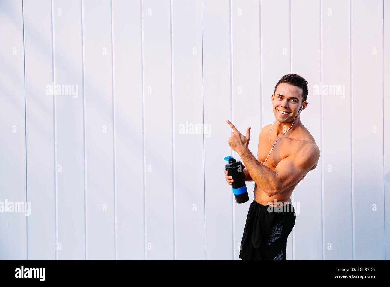 Smiling man with muscular body pointing finger on copyspace, holding a ...