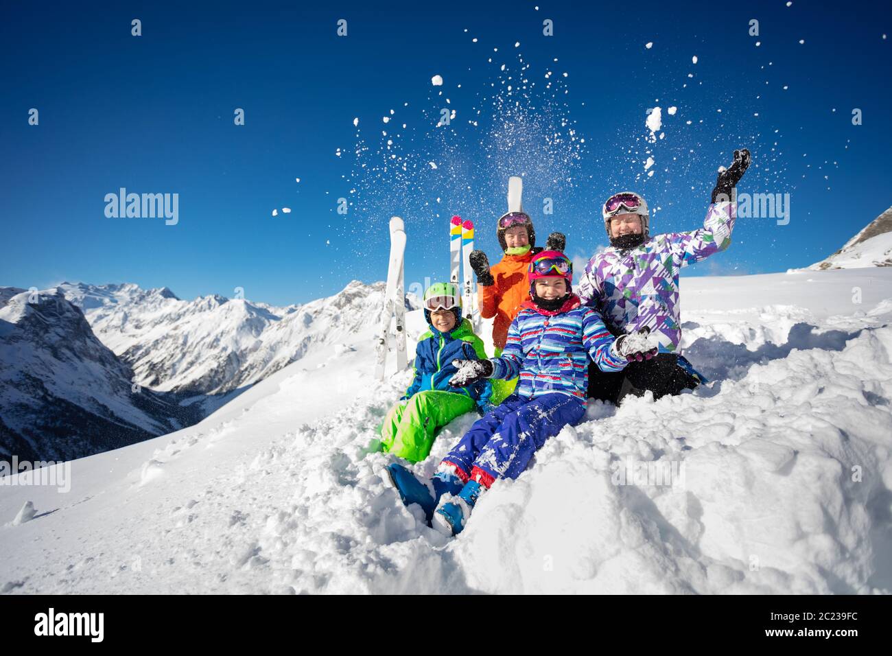 Group of ski school kids class in colorful outfit throw snow in the air ...